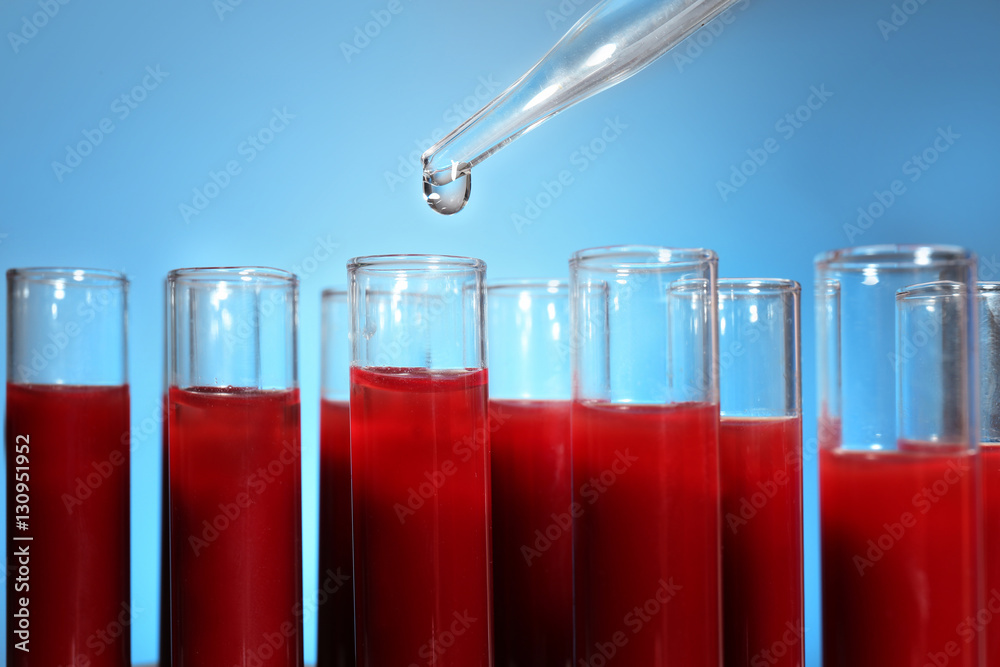 Test tubes filled with blood and glass dropper on blue blurred ...
