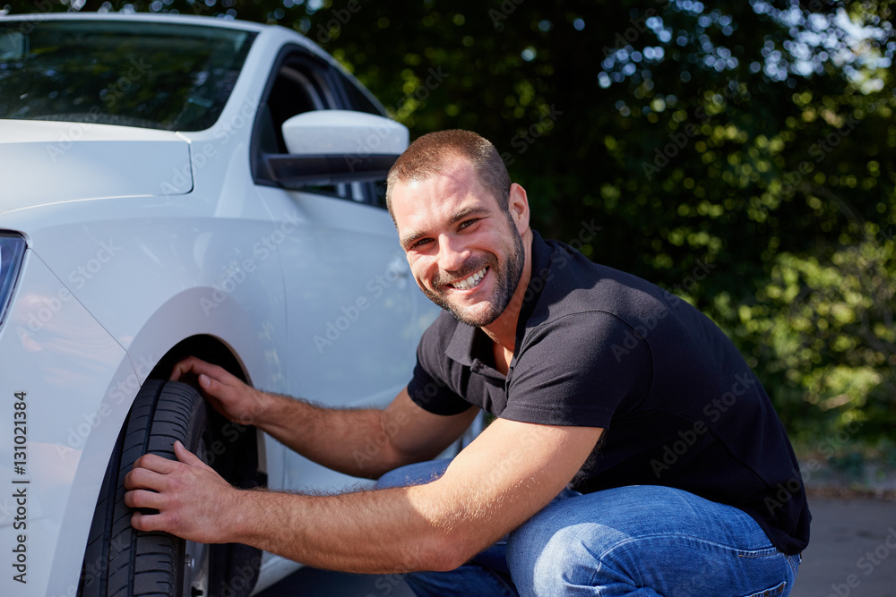 Smiling man examining tires at his new car Stock Photo | Adobe Stock
