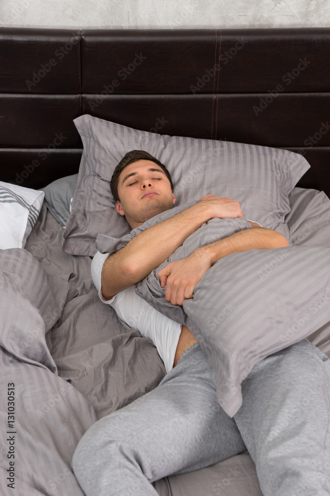 Handsome young tired man in pajama sleeping alone without blanke Stock ...