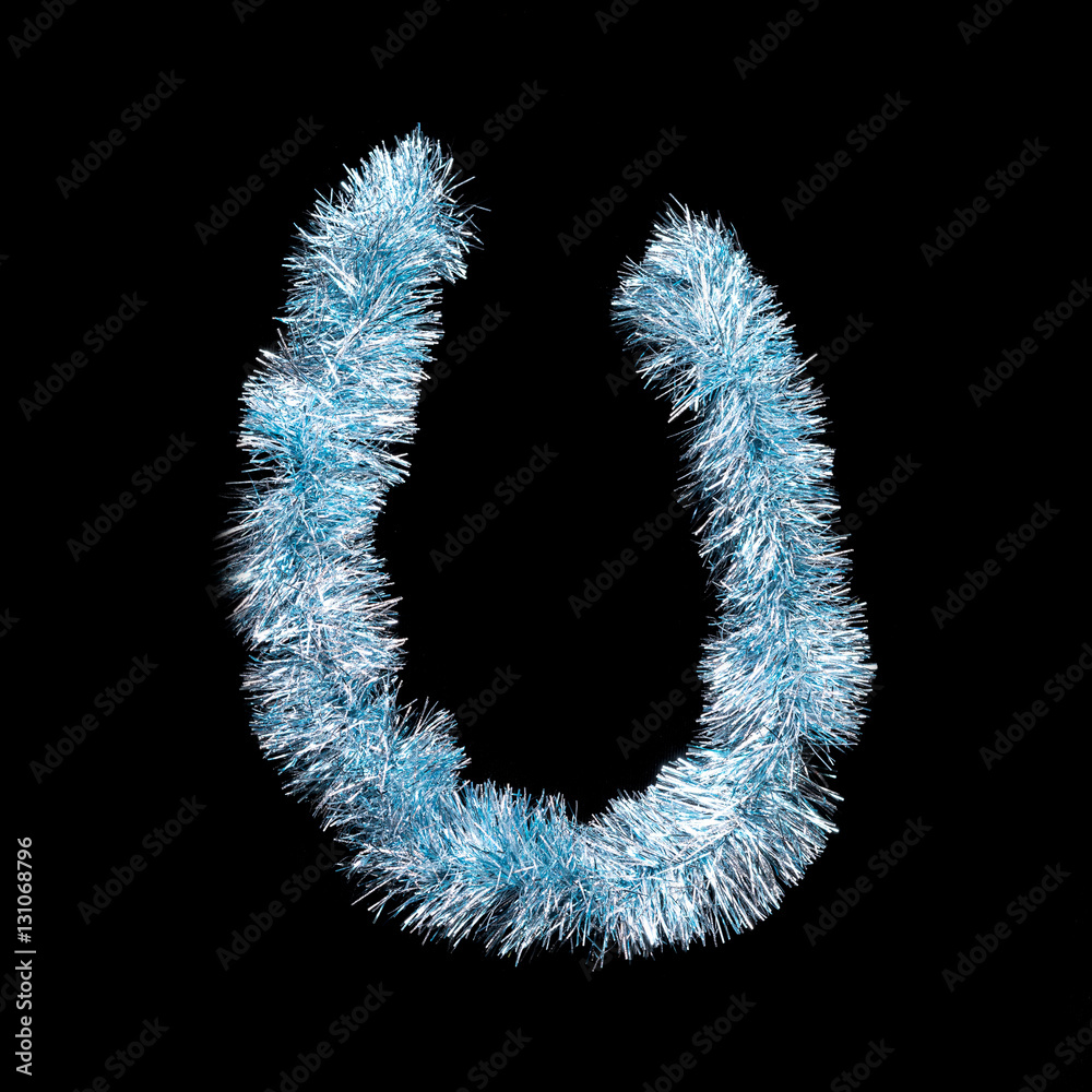 Festive alphabet made of blue tinsel. Letter U on black background ...