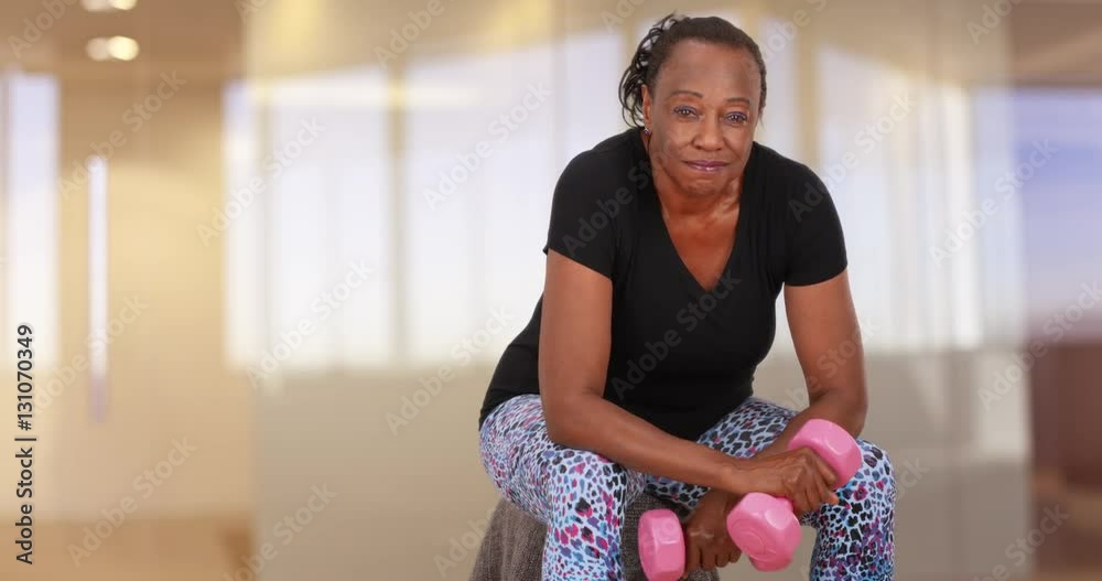 An older black woman poses for a portrait after lifting weights. An ...