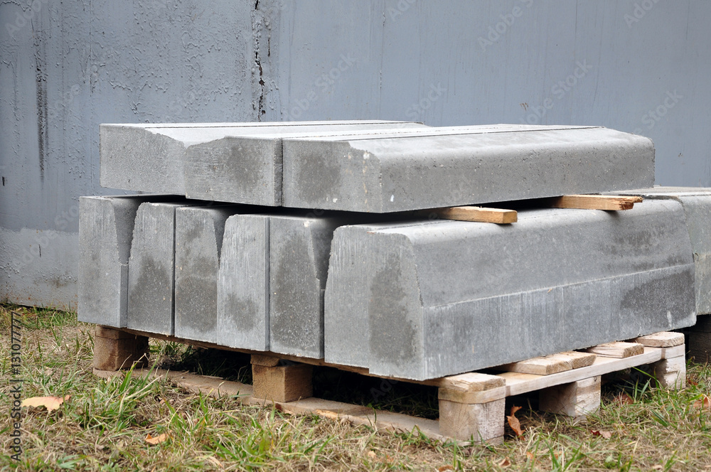 The construction process. The pallet with a stack of concrete curbstone ...