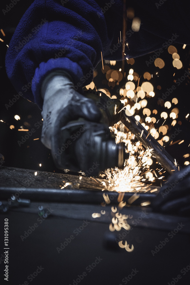 Out of focus image of industrial worker cutting metal pipe with sharp ...