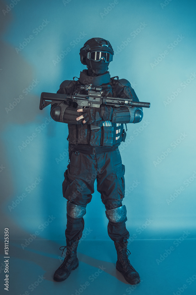 Member of the SWAT squad with an assault rifle in a black uniform on ...