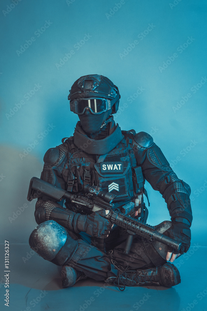 Member of the SWAT squad with an assault rifle in a black uniform on ...