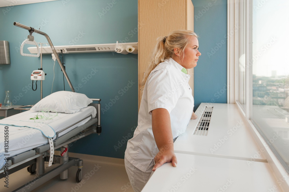 Nurse on hospital ward looking out of window Stock Photo | Adobe Stock