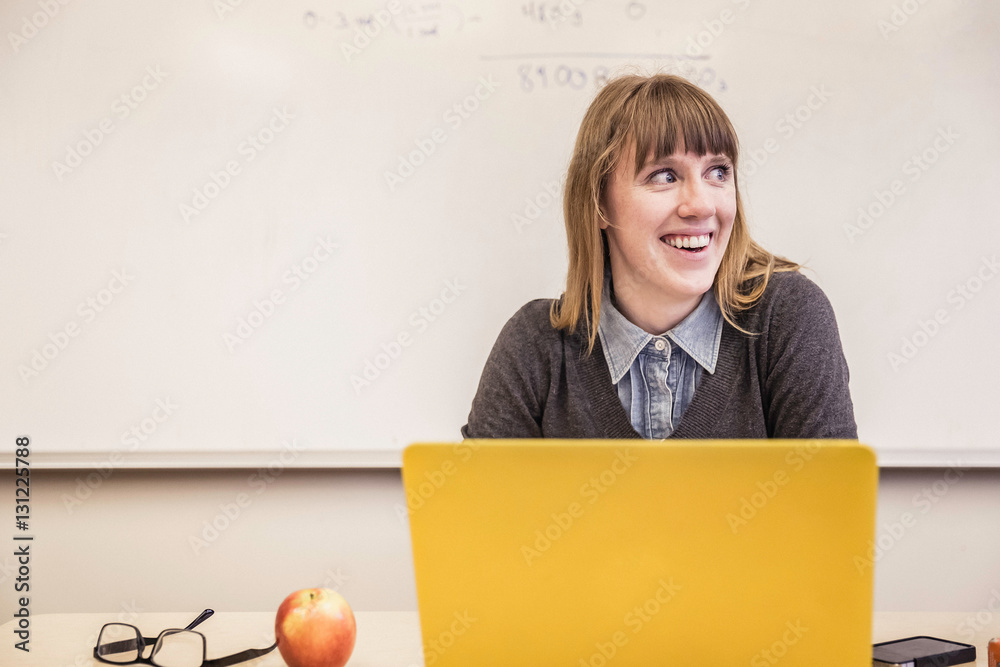Female teacher using laptop in front of whiteboard during high school ...