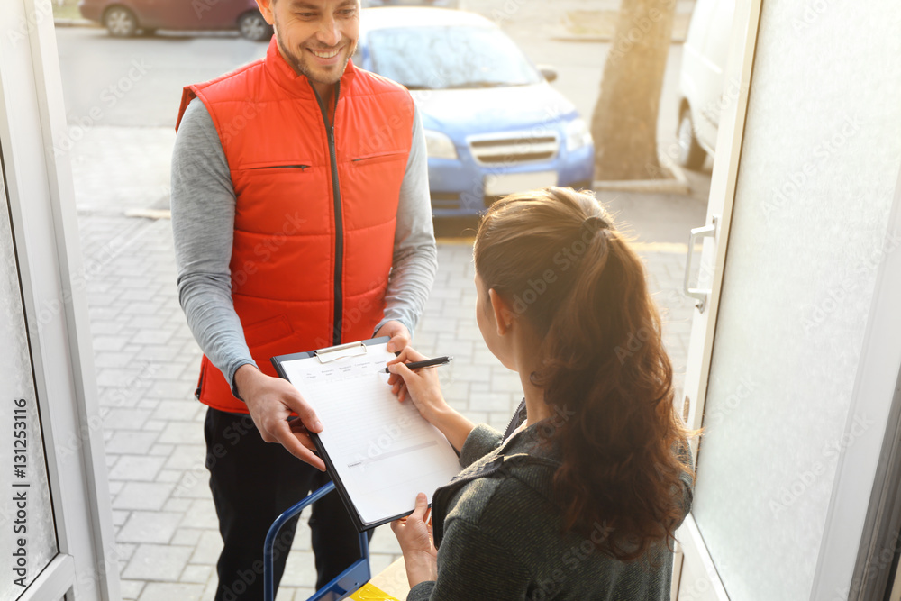 Young woman signing documents after receiving parcel from courier Stock ...