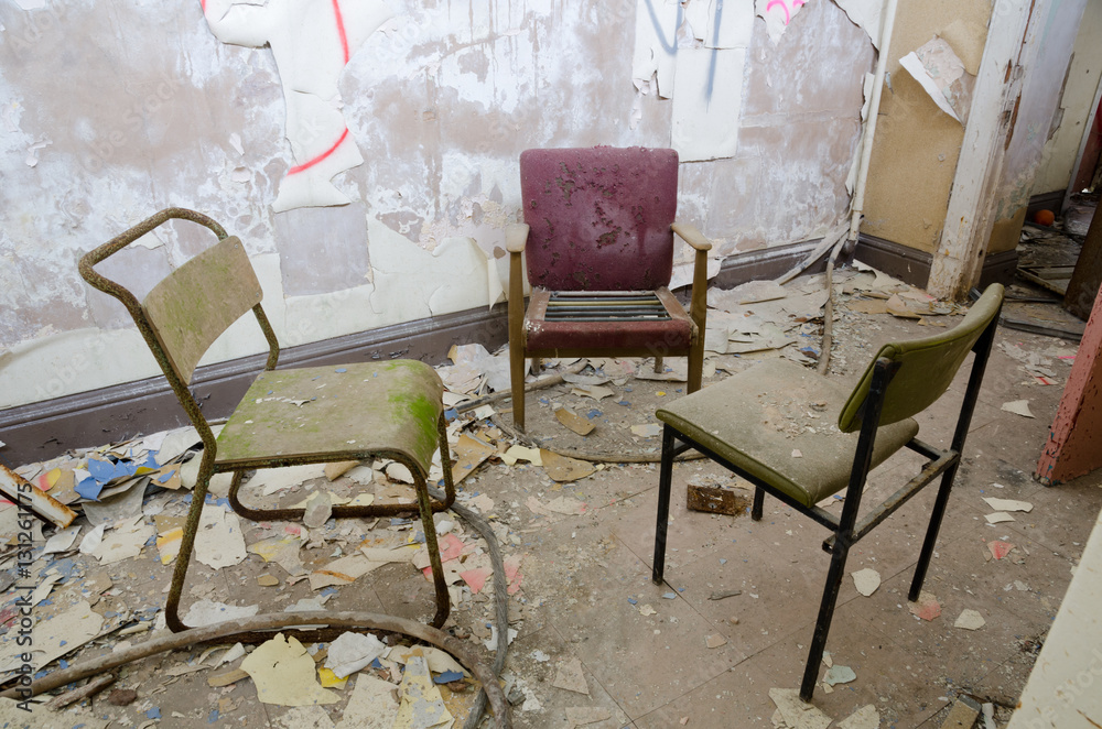 An old abandoned room with three dirty old office chairs, in a decaying ...
