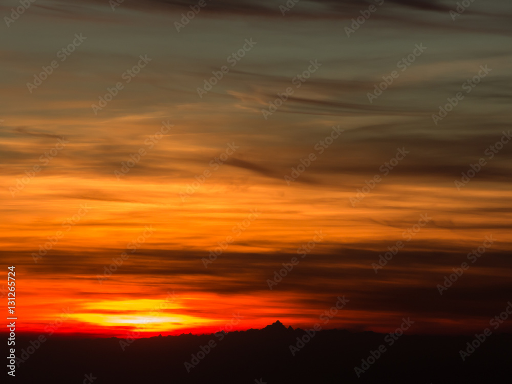 Fiery sunset from mountain pick with thin glazes in the sky evening ...
