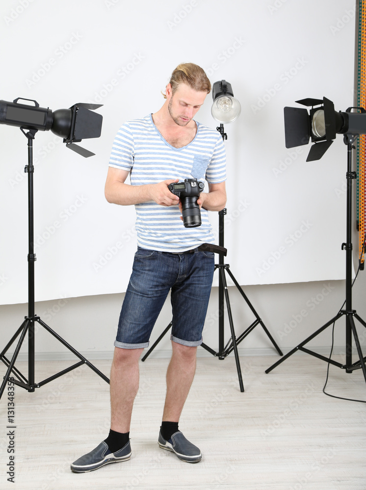 Handsome photographer with camera at working, on photo studio ...