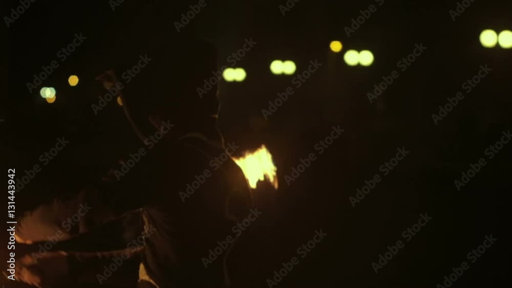 Fire show performance. Handsome male fire performer twirling fire baton ...