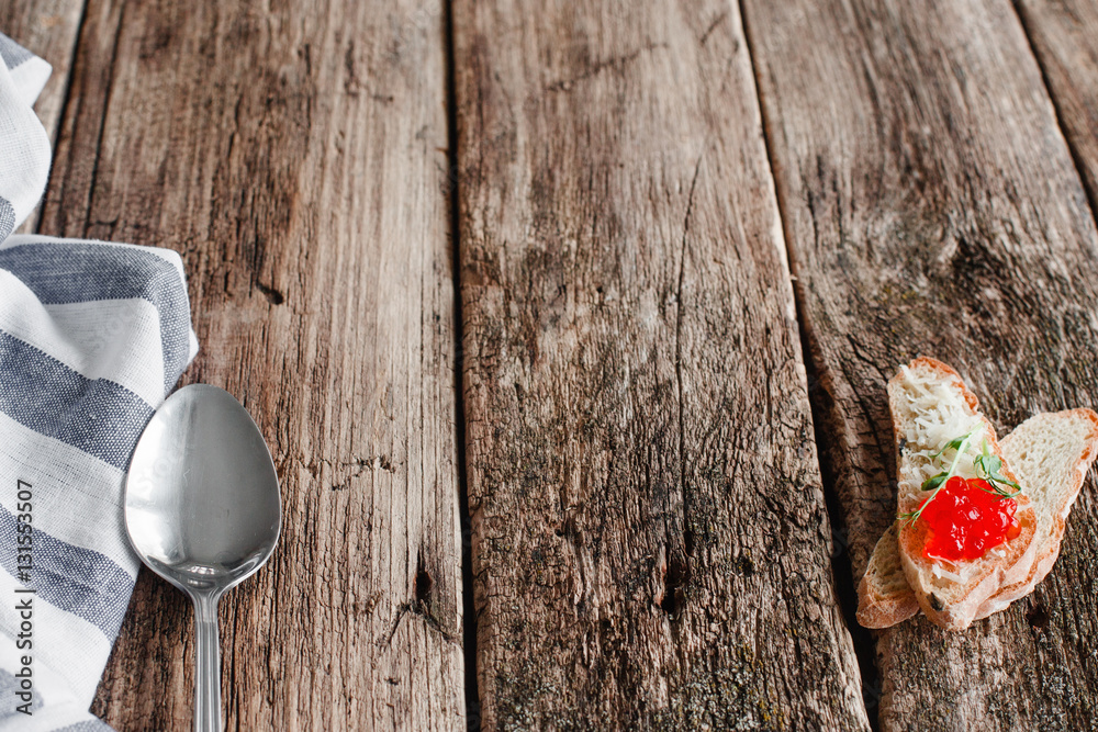 Canape with red caviar and spoon on wood void. Empty rustic table with ...