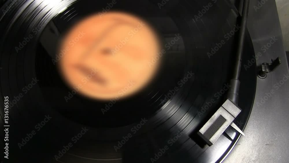 Old turntable with a vinyl and the tone arm rotate. The camera shows ...
