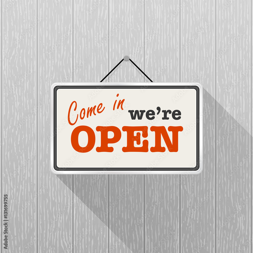 Simple white sign with text "Come in we're open" hanging on a gray ...