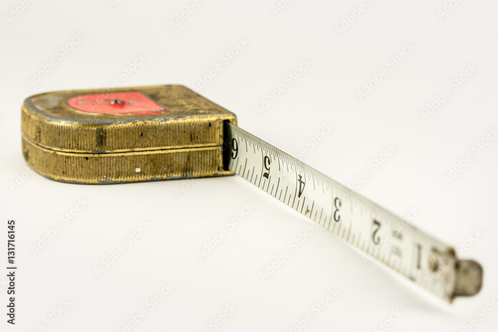 Old gold colored steel tape measure with 1 through 6 inch marks exposed ...