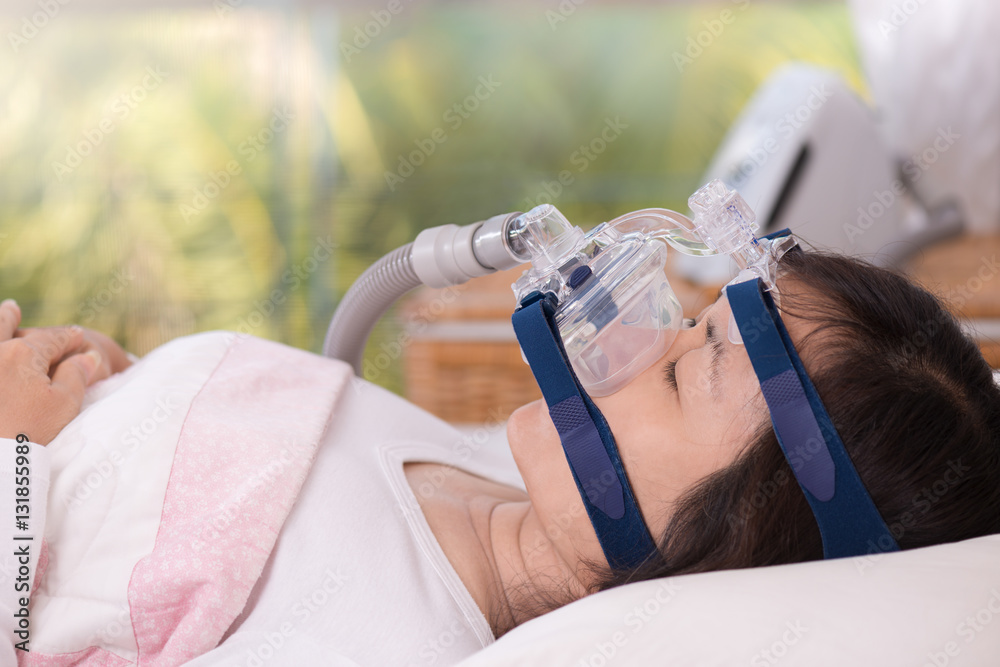 Sleep apnea therapy, Woman sleeping in bed wearing CPAP mask.Happy and ...