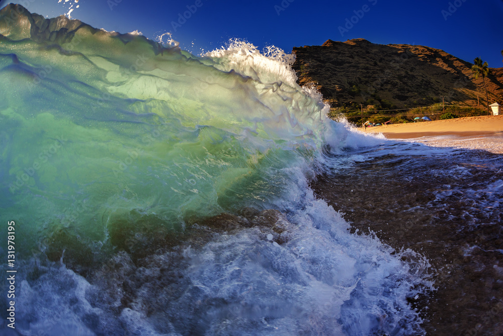 Sea waves crashing against shore at tropical beach with mountain wall ...