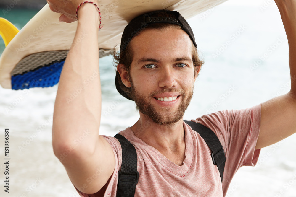 People, hobby and leisure concept. Happy young bearded surfer holding ...