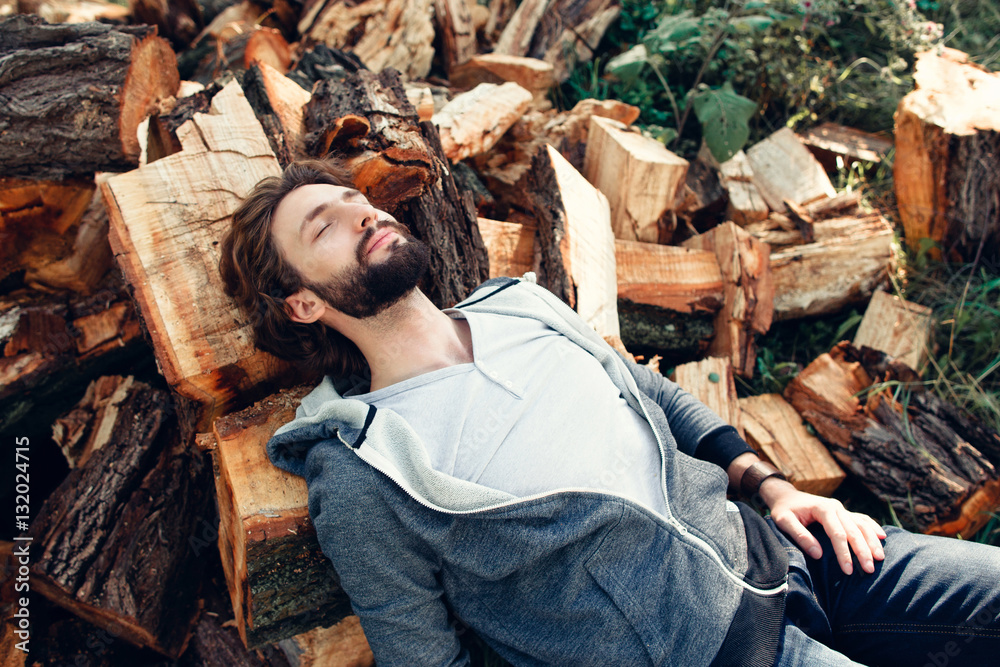 Tired lumberjack sleeping on pile of wood. Exhausted woodcutter having ...