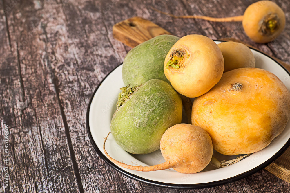 Turnip. White metal a plate with turnip on a cutting board on an old ...