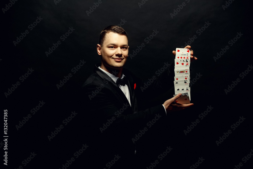 Closeup of man magician with two playing cards in his hand over grey ...