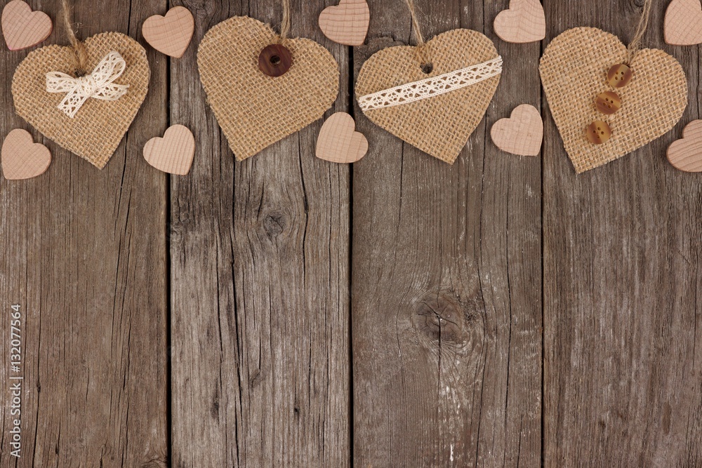 Top border of handmade burlap hearts with ribbon and buttons over a ...