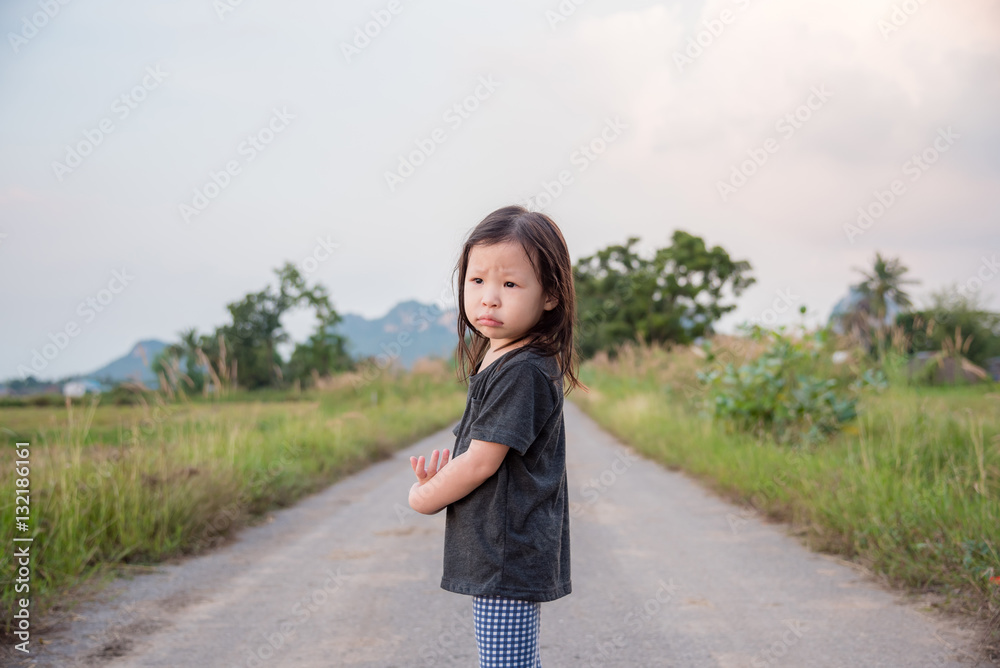 Foto Stock Sad little asian girl standing alone on street | Adobe Stock