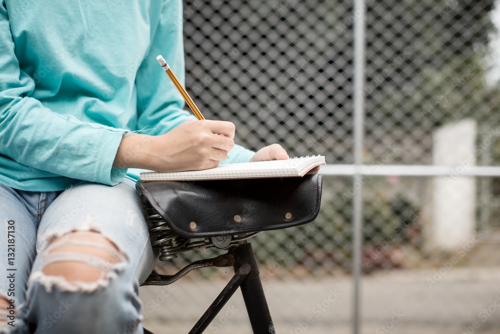 Female asian girl writing a notebook while sitting a bicycle out Stock ...