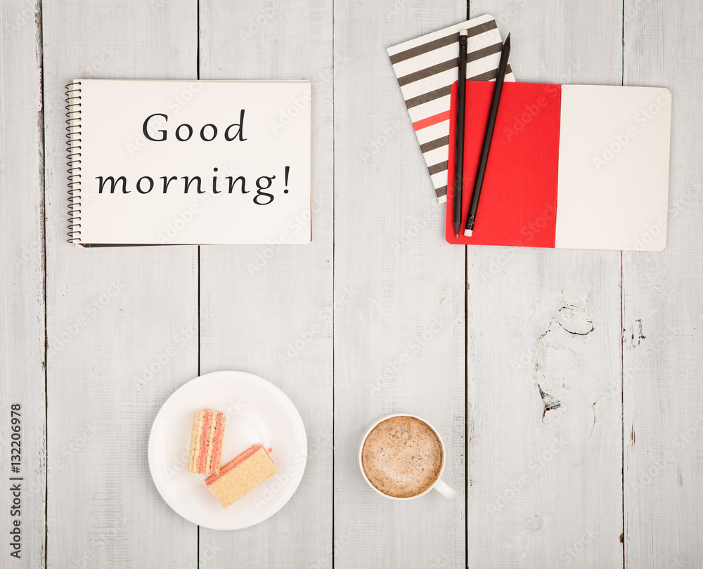 Office table with notepads and text "Good morning!", cup of coffee and ...