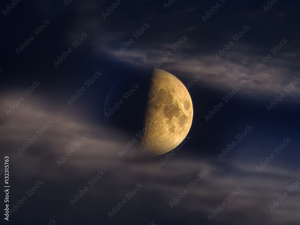 Half moon seen through gray night clouds on dark blue sky. This is high ...