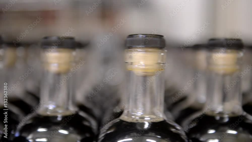 Rows of glass bottles filled with maple syrup at a bottling plant ready ...
