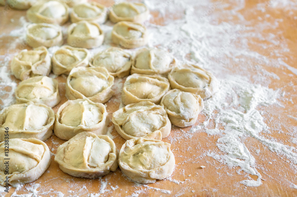 Preparation of manti (manty) on a kitchen wooden board. Traditional ...