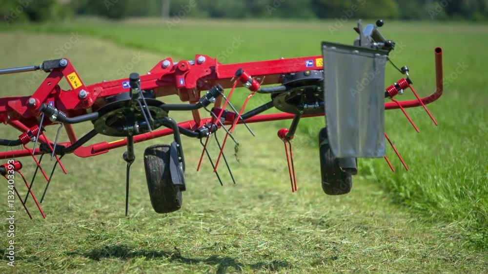 A tractor is slowly lowering down rotary hay rakes that are connected ...