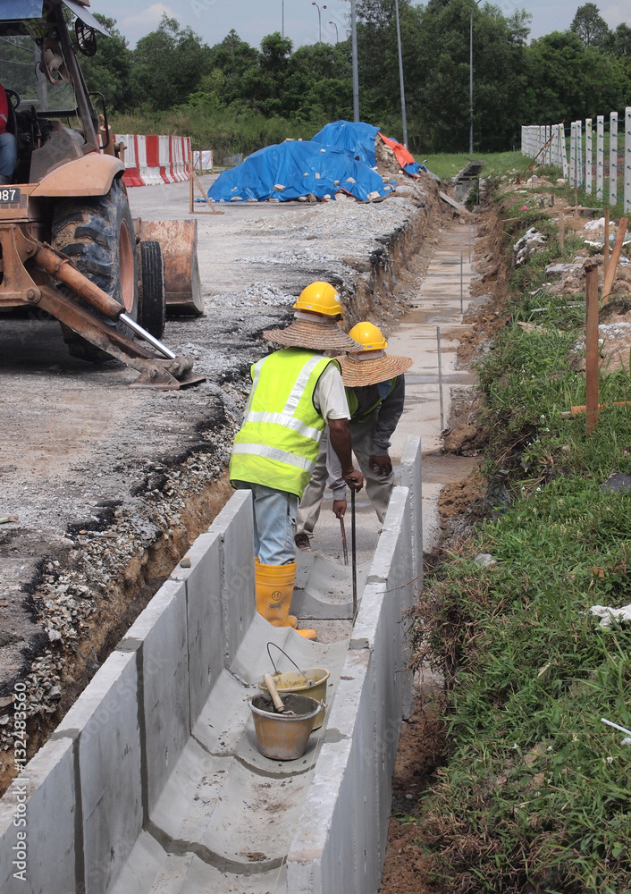 Group of Construction workers installing precast concrete drain at the ...