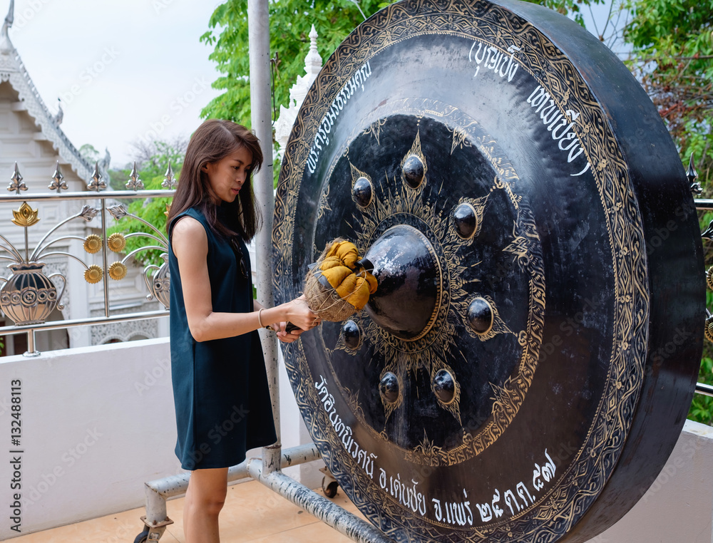 Foto de thai young adult woman hold wooden hammer to hit big circle ...