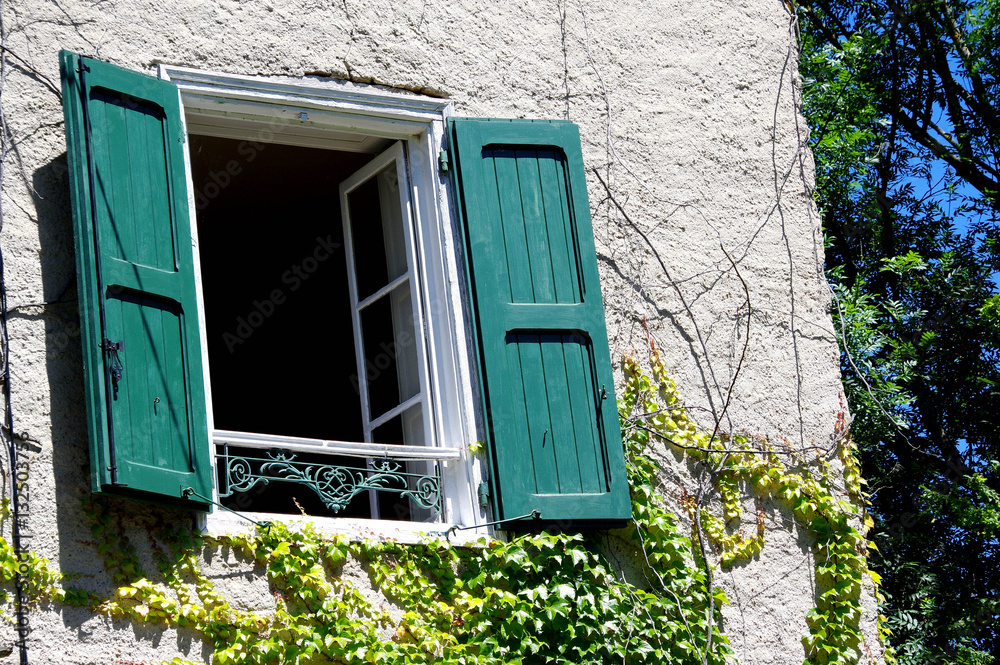 fenêtre et volets ouvert sur une façade de maison Photos | Adobe Stock