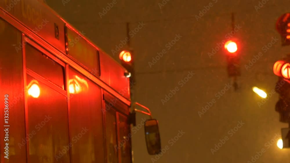Bus is waiting at the red semaphore light during a night snowfall ...