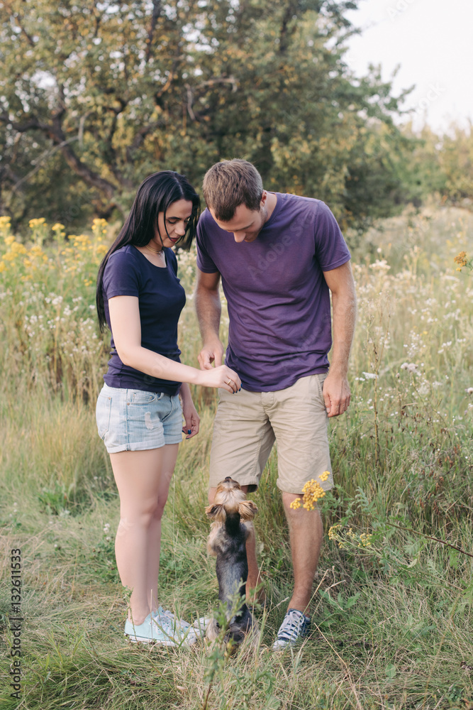 Young happy couple posing with their dog - yorkshire terrier on nature ...