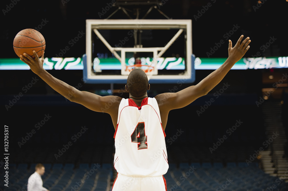 Basketball player standing in basketball court with arms outstretched ...