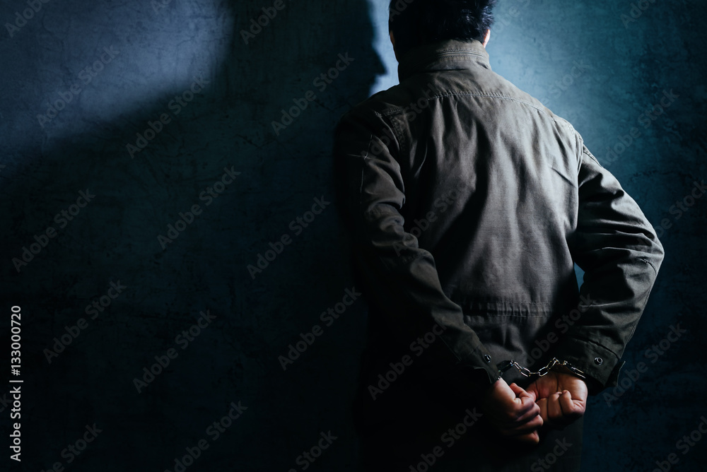 Arrested male criminal with handcuffs facing prison wall Stock Photo ...