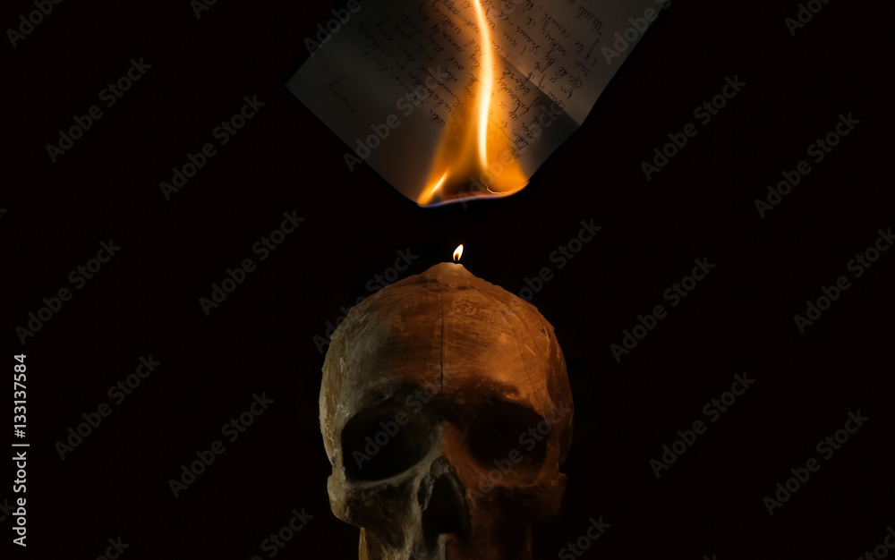 Burning handwritten letter by candle fire on skull sculpture Stock ...