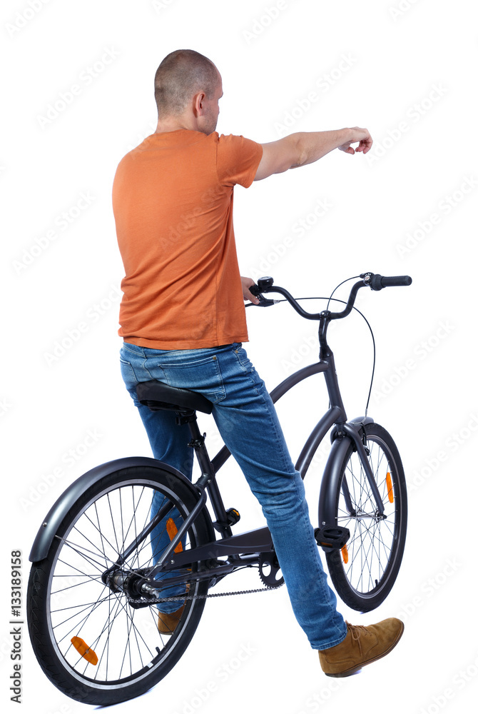 back view of pointing man with a bicycle. cyclist sits on the bike ...