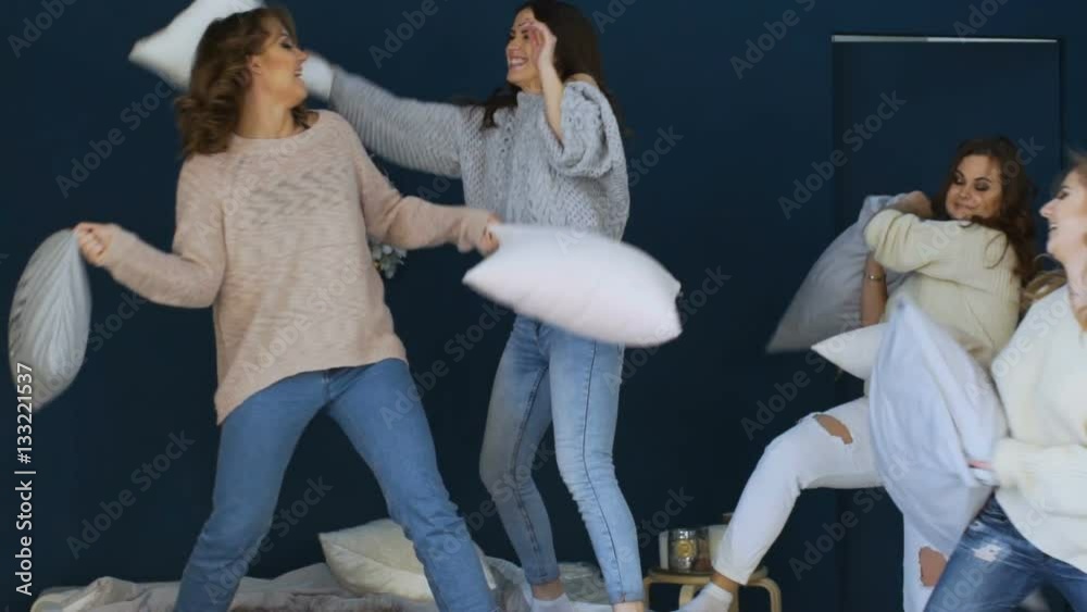 Four beautiful girls fight pillows each other on bed slowmotion Stock ...