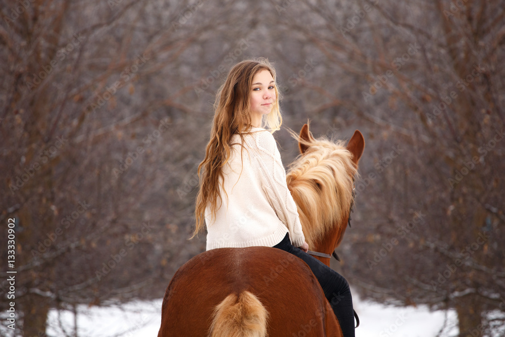 Cute girl looking back over shoulder riding horse in forest Stock Photo ...