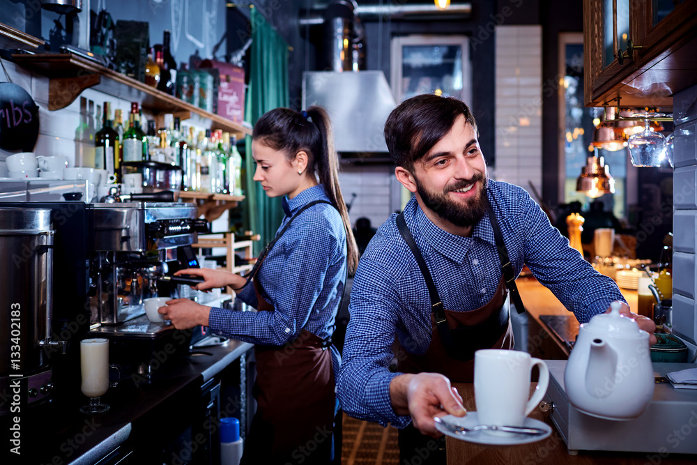 Bartender waiter with a kettle and mug of coffee tea working in the ...