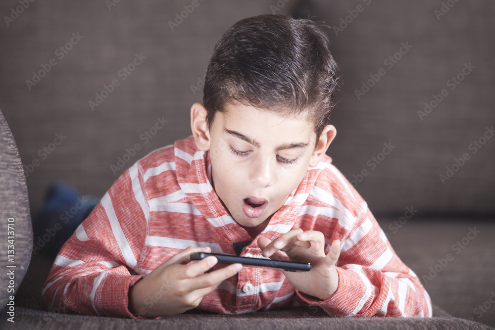 Young boy reacts while watching inappropriate content on his smartphone ...