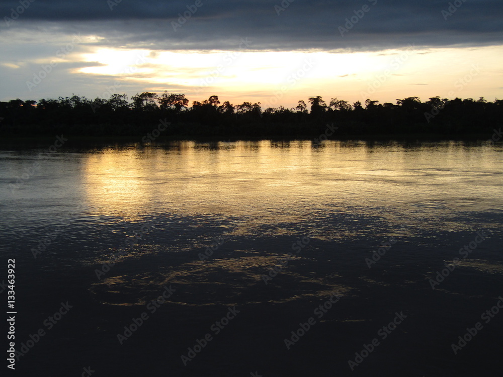 anochecer sobre el rio amazonas de peru con franja de vegetacion a ...