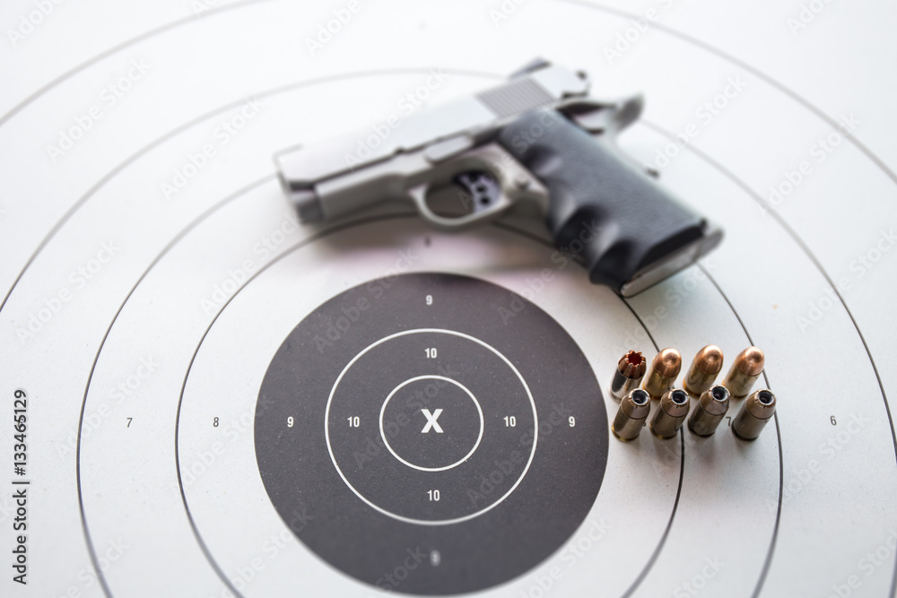 Foto Stock type of .45 bullets on bullseye target with blurred pistol ...