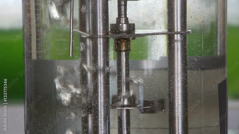 Laboratory fermenter (bioreactor) works filled with water. Air bubbles ...